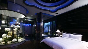 Quarto de hotel moderno com uma cama grande, um expositor de vidro com flores e vista para a cidade.