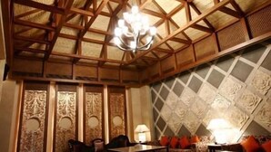 Um quarto amplo com teto de madeira alto, paredes com padrão e piso lustroso.