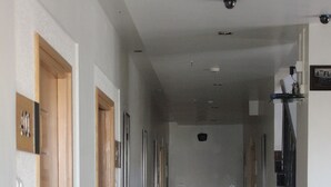 Um corredor com portas de madeira, piso ladrilhado e escada à direita.