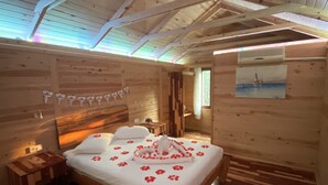 Quarto de cabana de madeira com cama, mesa de cabeceira e um quadro na parede.