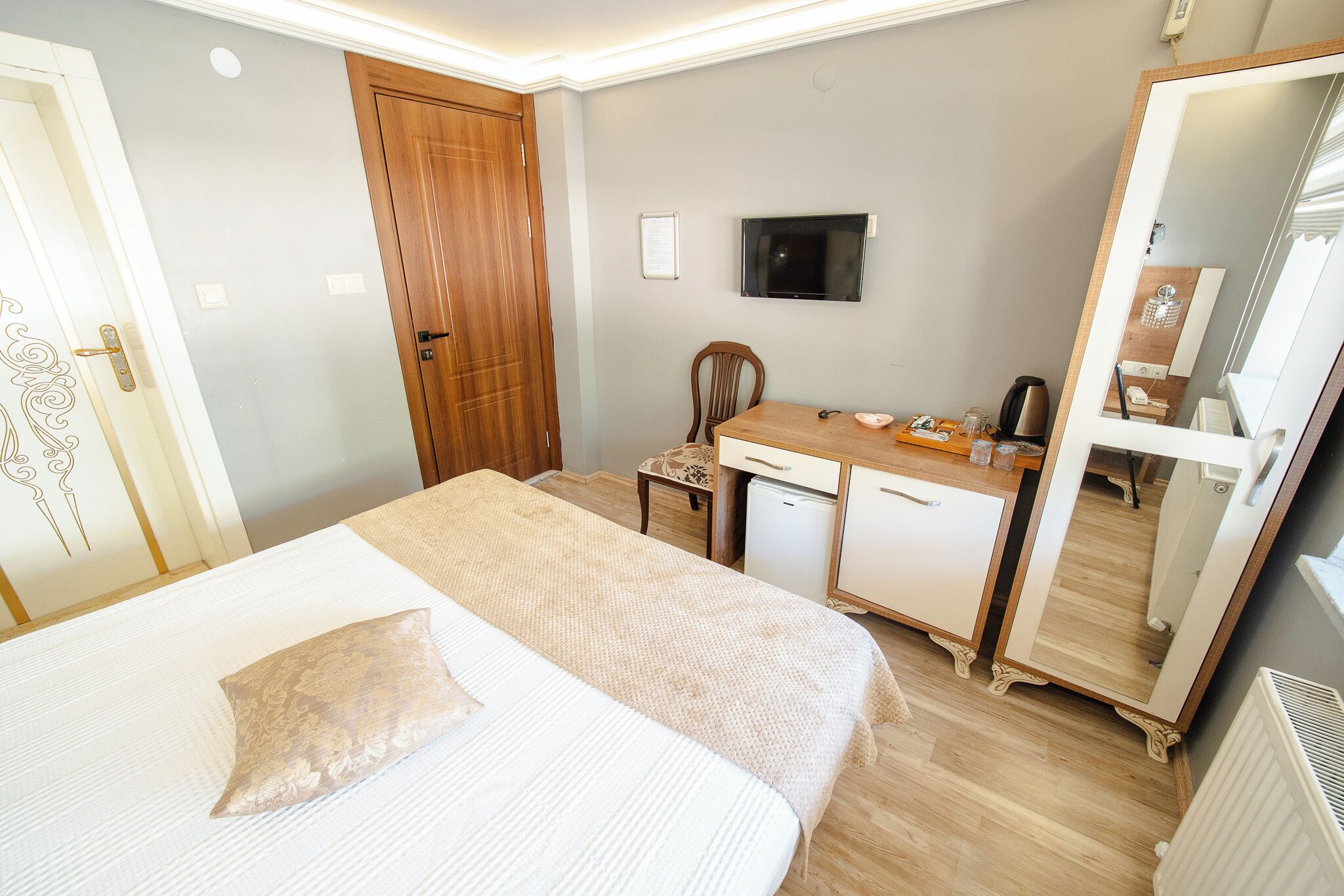 Quarto com cama, escrivaninha, cadeira, televisão e armário.