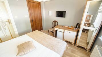 Quarto com cama, escrivaninha, cadeira, televisão e armário.