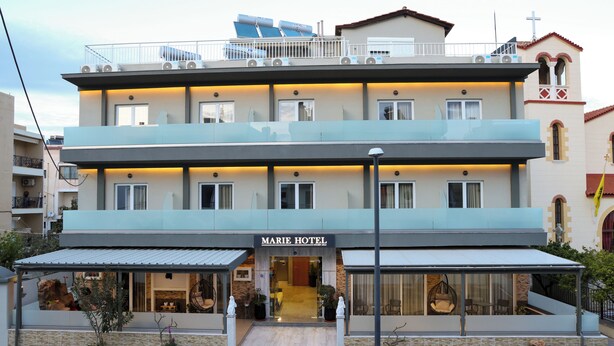 Hotel de dois andares com varanda, entrada coberta e escadaria visível.