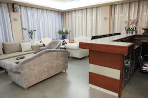 Uma sala de estar moderna com um sofá, uma mesa de centro e uma área de jantar com uma mesa comprida e cadeiras.