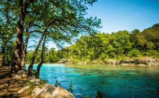 Um rio com águas cristalinas, cercado por árvores e pedras.