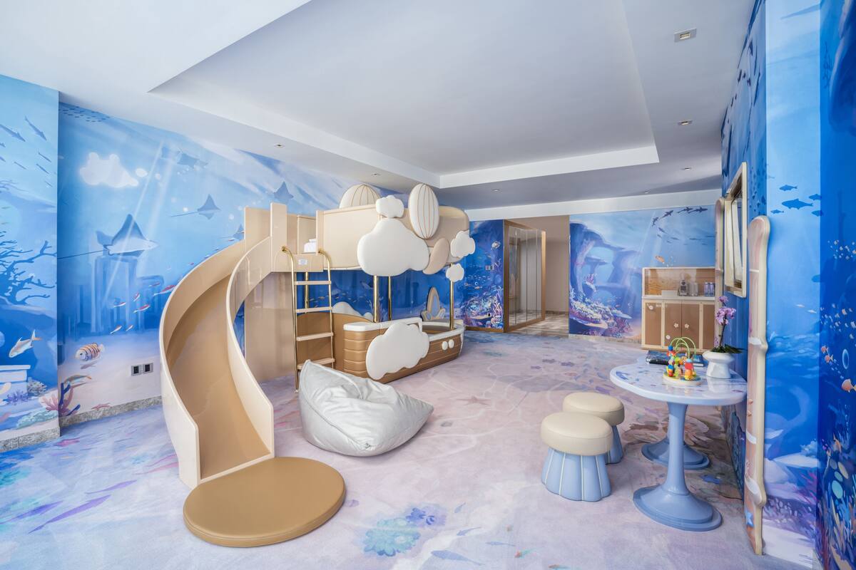 Uma sala de jogos infantil com escorrega, espaço de recreação e um mural.