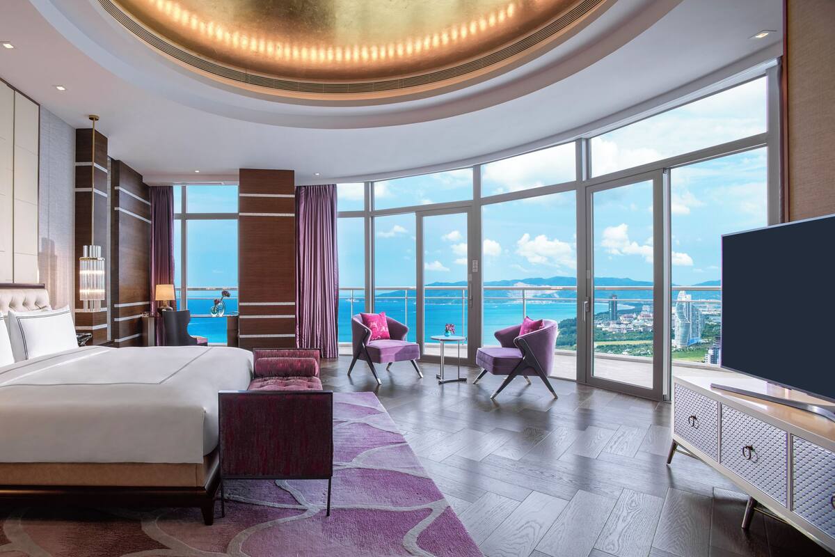 Quarto de hotel moderno com uma cama grande, televisão e vista para o mar.