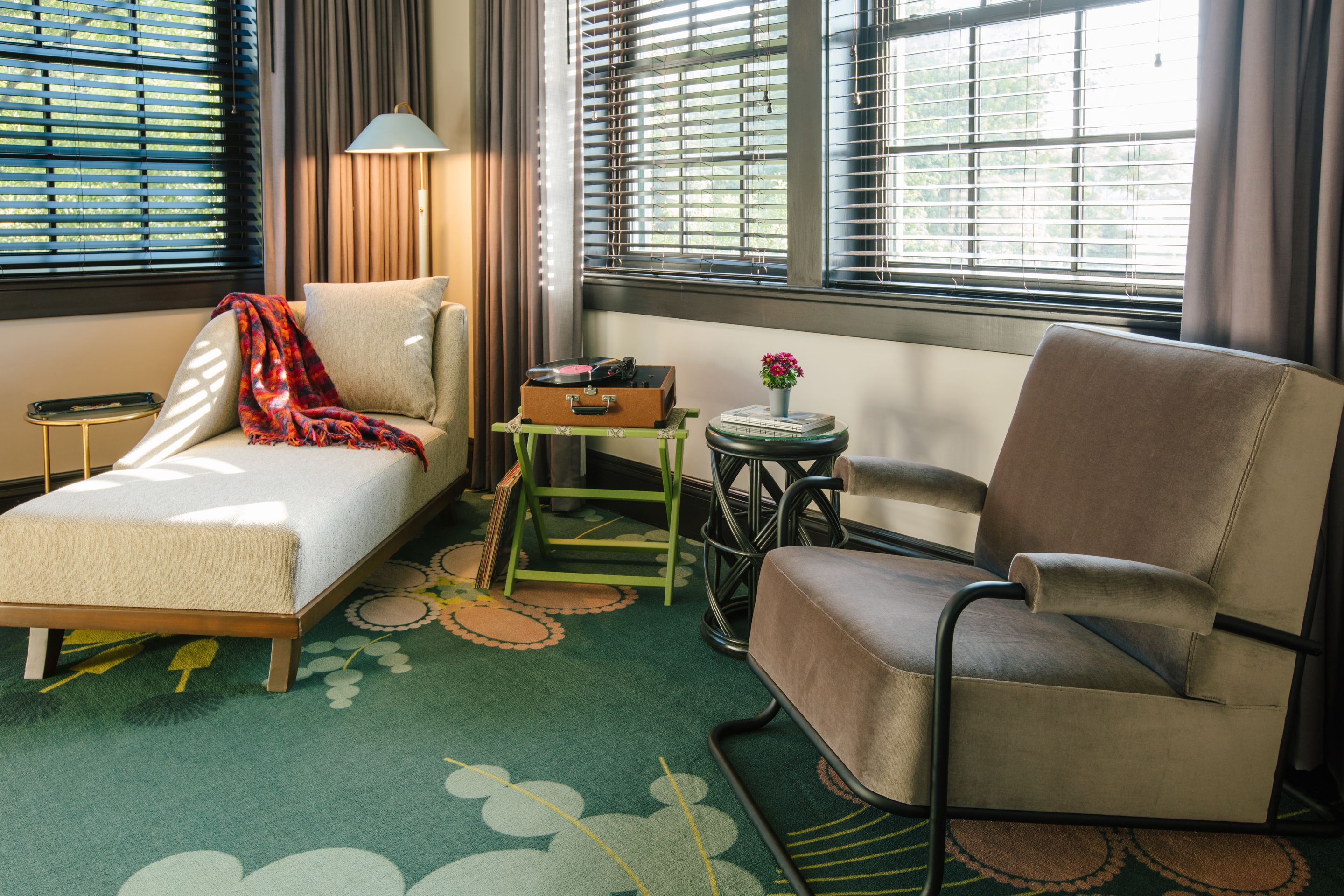 Um quarto aconchegante com sofá, poltrona, mesa pequena e luminária.