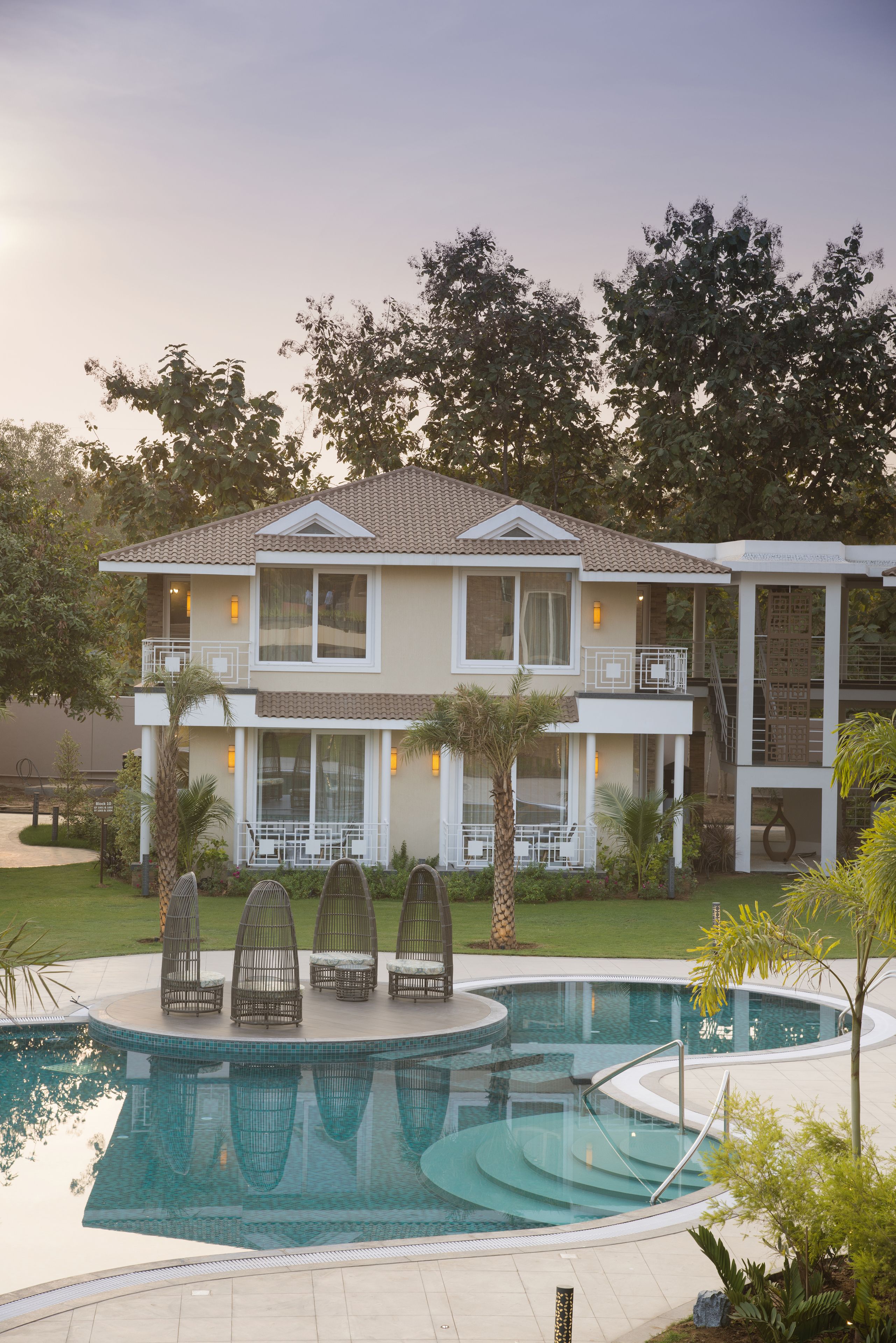 Uma casa de dois andares com piscina, área de estar externa e escada que dá para uma varanda.