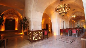 Um hall amplo com tetos altos em arco, paredes de pedra e lustres elaborados.