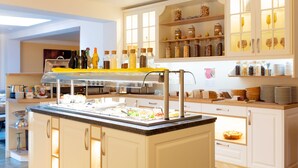 Uma mesa de buffet com diversas opções de comida, um espaço para café e uma seleção de vinhos.