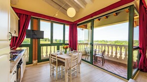 Uma sala de jantar com uma mesa posta para quatro pessoas, janelas amplas e vista para o verde lá fora.