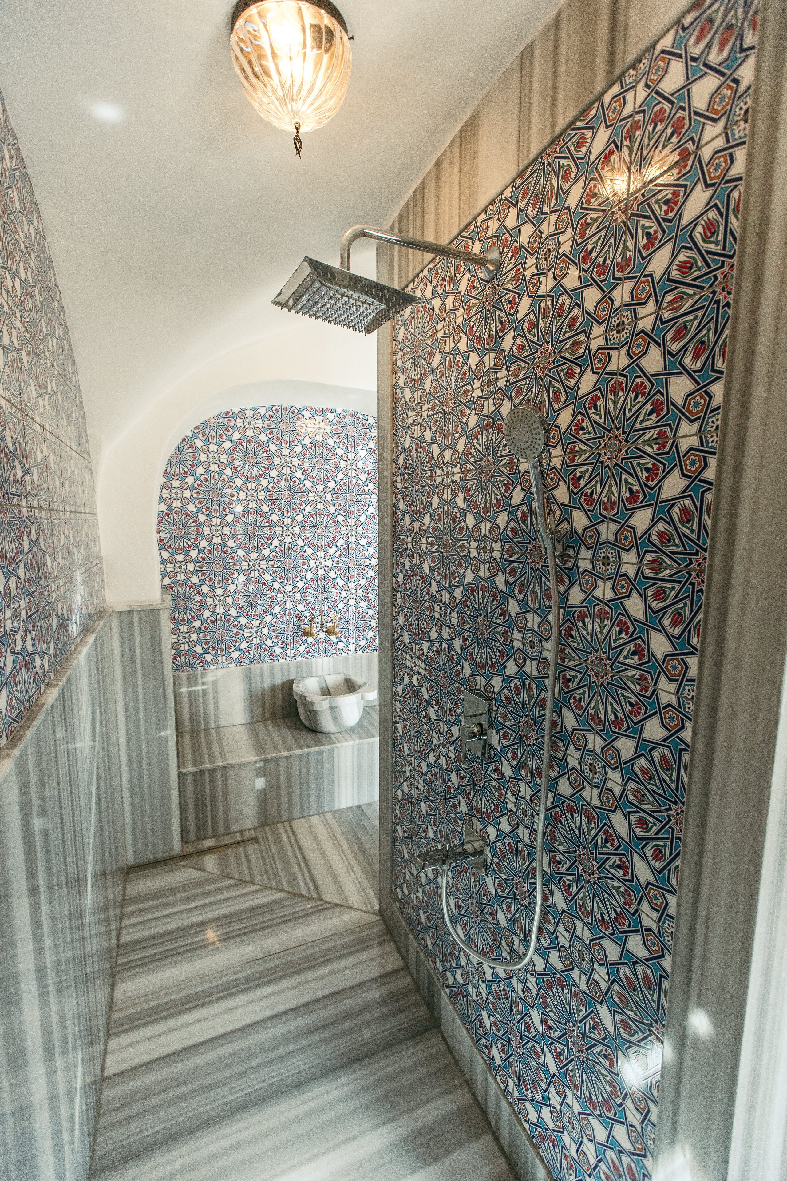 Um banheiro moderno com azulejos estampados, chuveiro e piso de mármore.