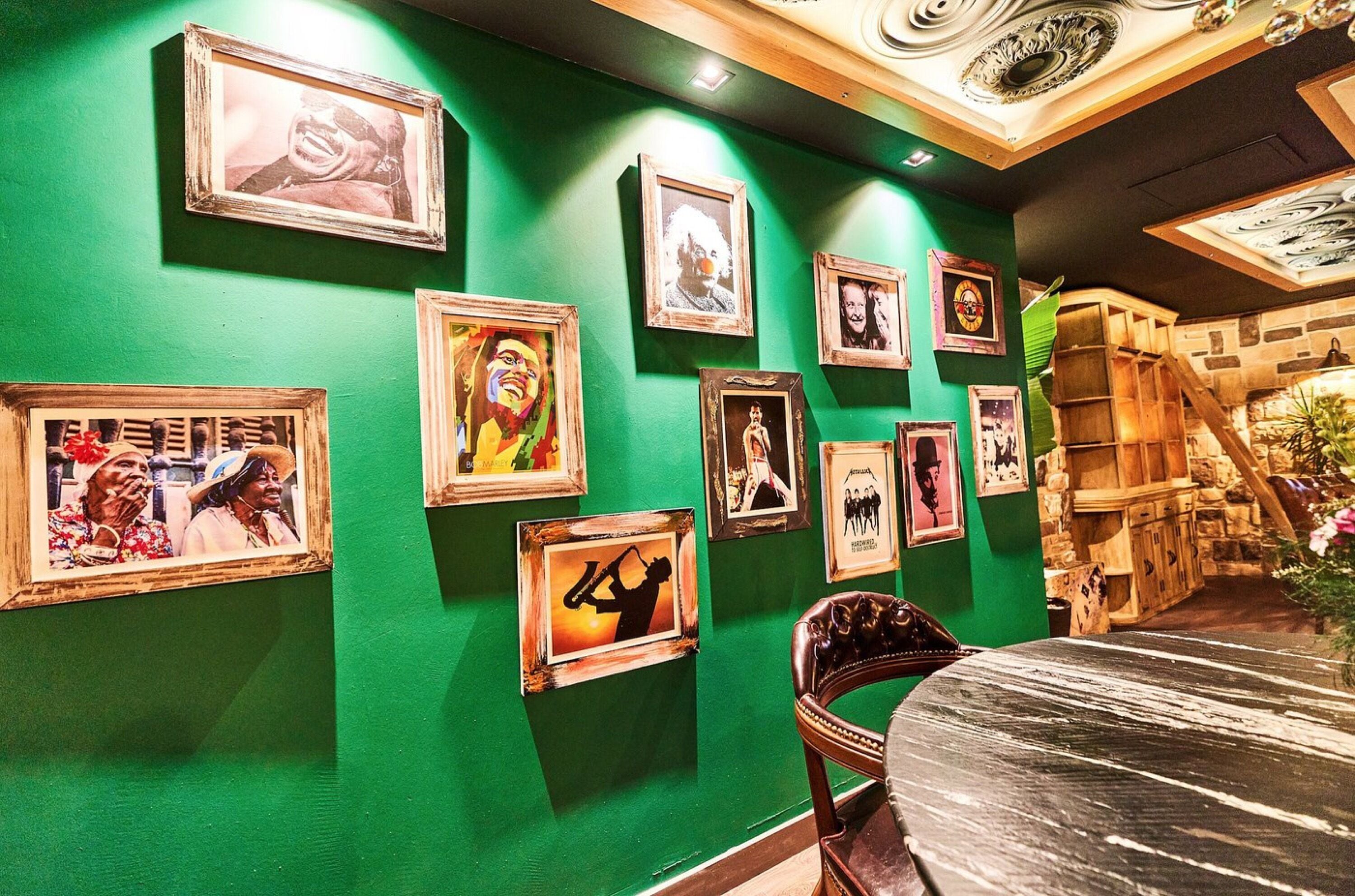 Quarto com paredes verdes, móveis de madeira e várias imagens emolduradas na parede.