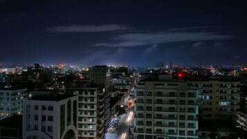 Paisagem urbana noturna com edifícios e uma rua movimentada.