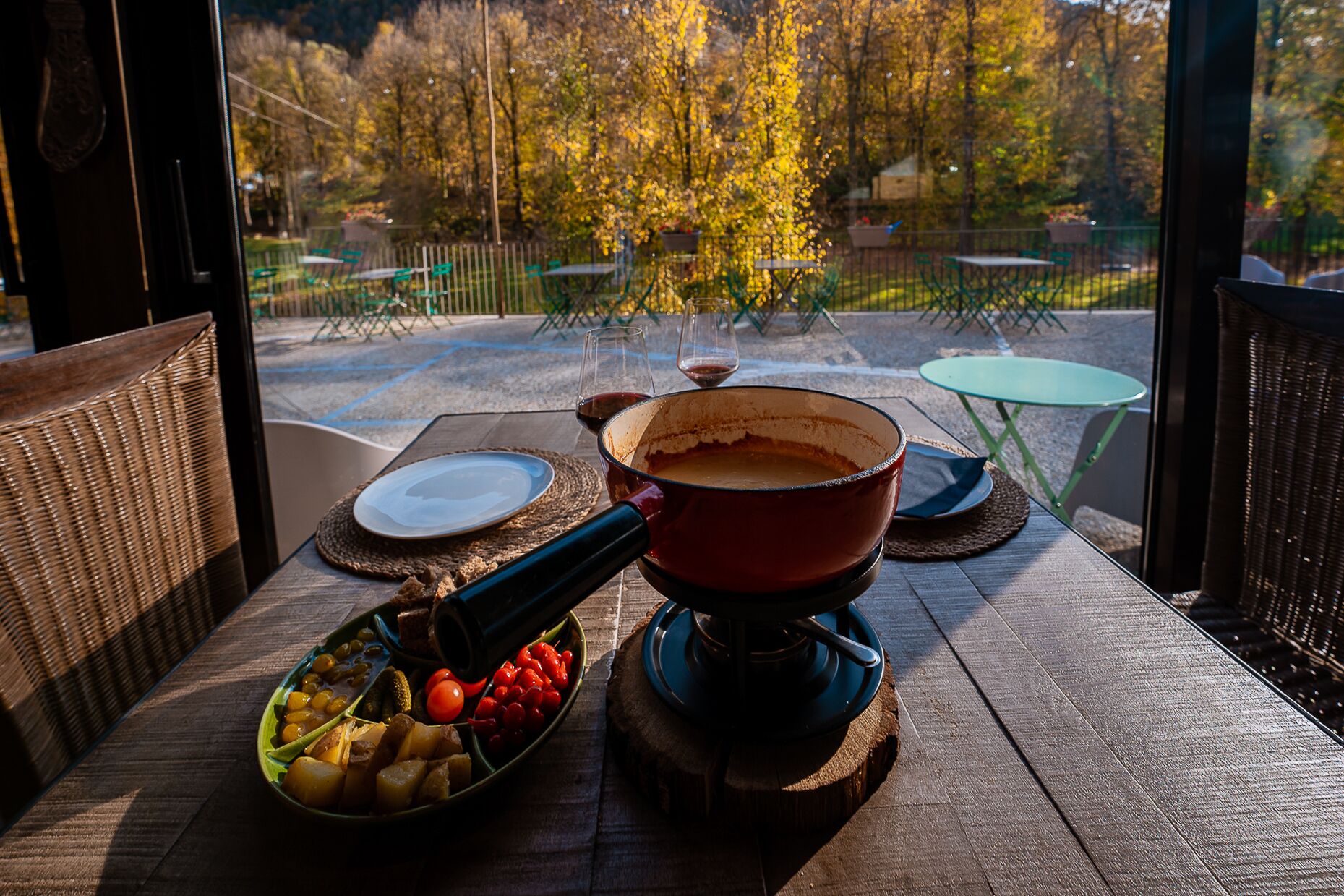 Uma mesa de jantar com uma panela de sopa, um prato de legumes e uma garrafa de vinho.