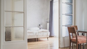 Quarto com cama, cadeira, mesa e janela.