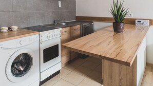 Cozinha moderna com armários de madeira, forno embutido, máquina de lavar e uma ilha grande com uma planta.