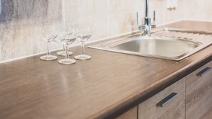 Uma cozinha com armários de madeira, bancada de granito e pia de aço inoxidável.