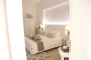 Quarto com cama, mesas de cabeceira, guarda-roupa e janela com persianas.
