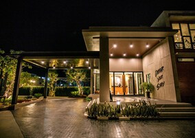 Uma entrada de hotel moderna com galeria coberta, portas de vidro e um letreiro que diz 'Dine Your Stay'.