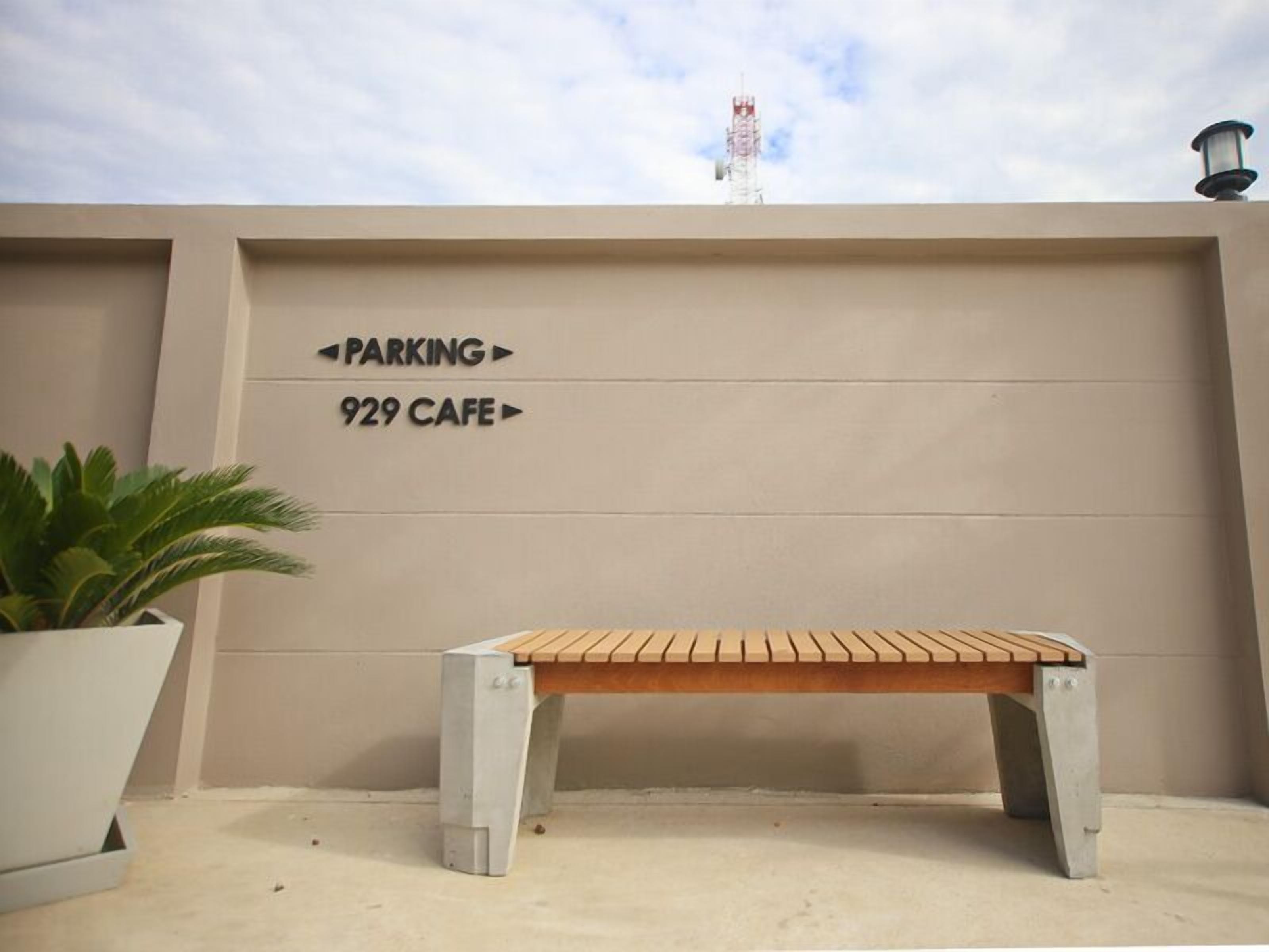 Parede com placas de sinalização para 'PARKING' e '929 CAFE'.