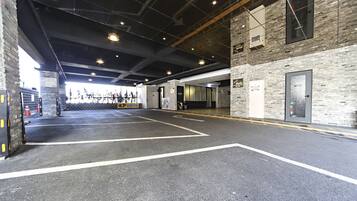 Um parque de estacionamento interior com vagas demarcadas, uma parede de tijolo e uma porta à direita.