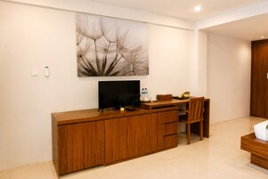 Quarto de hotel moderno com escrivaninha de madeira, televisão de tela plana e uma grande pintura abstrata na parede.