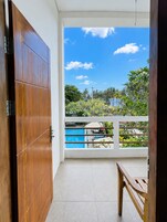 Porta de madeira que dá para uma varanda com vista para uma piscina e móveis de exterior.