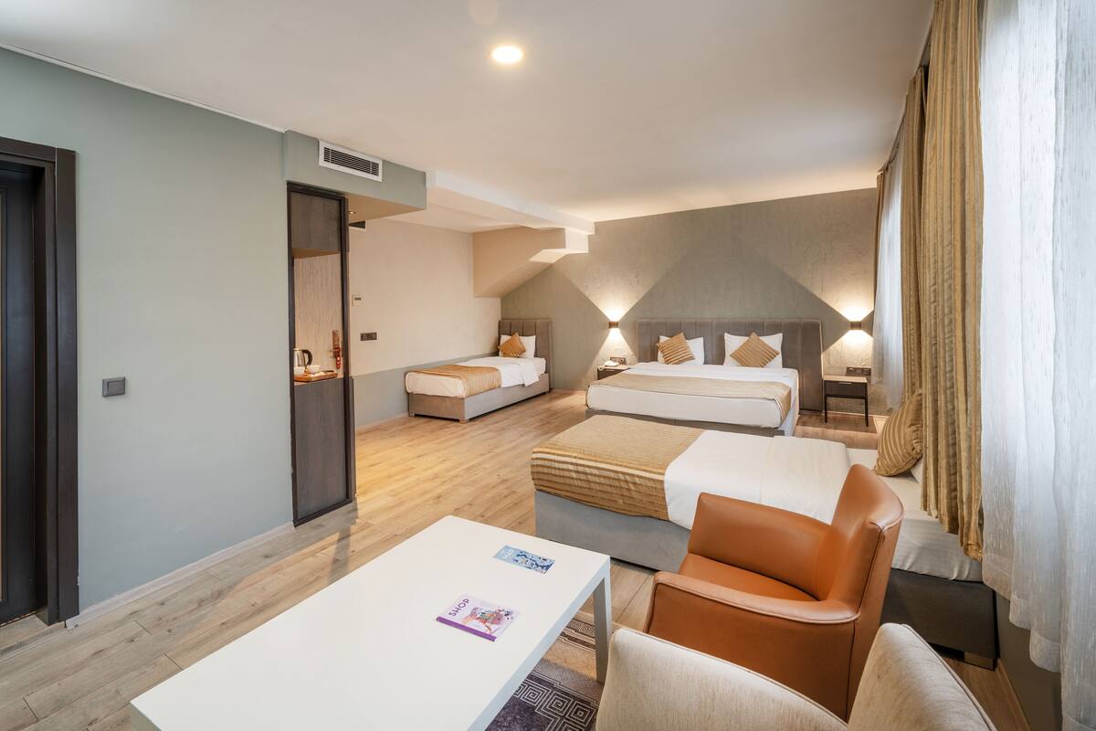Quarto de hotel com cama, sofá, mesa de centro e escrivaninha.