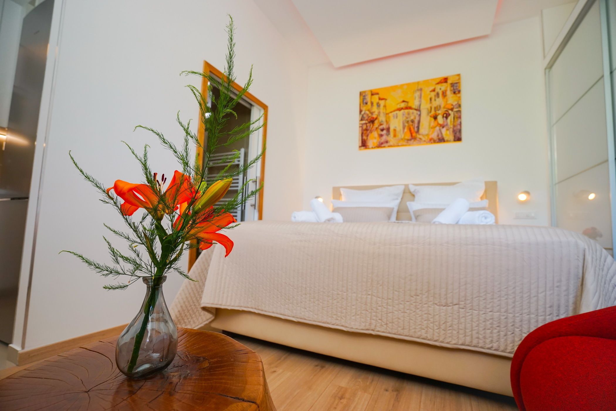 Quarto de hotel com uma cama, um vaso com flores e um quadro na parede.