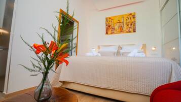 Quarto de hotel com uma cama, um vaso com flores e um quadro na parede.