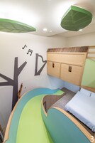Quarto com cama, um armário de madeira e parede com uma nota musical e símbolo de harpa.