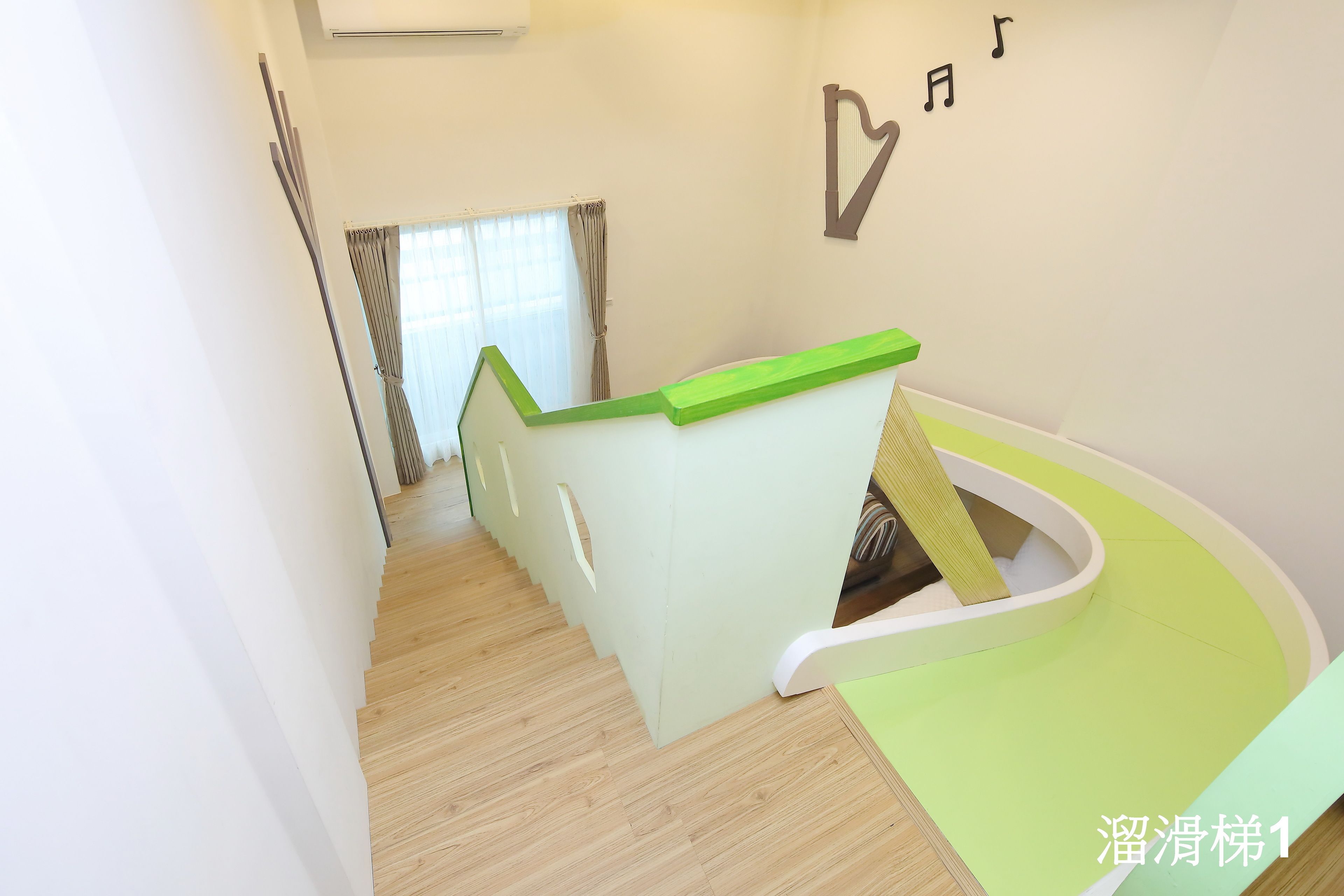 Um interior moderno com uma mesa de recepção curva, uma escadaria e uma harpa fixada na parede.