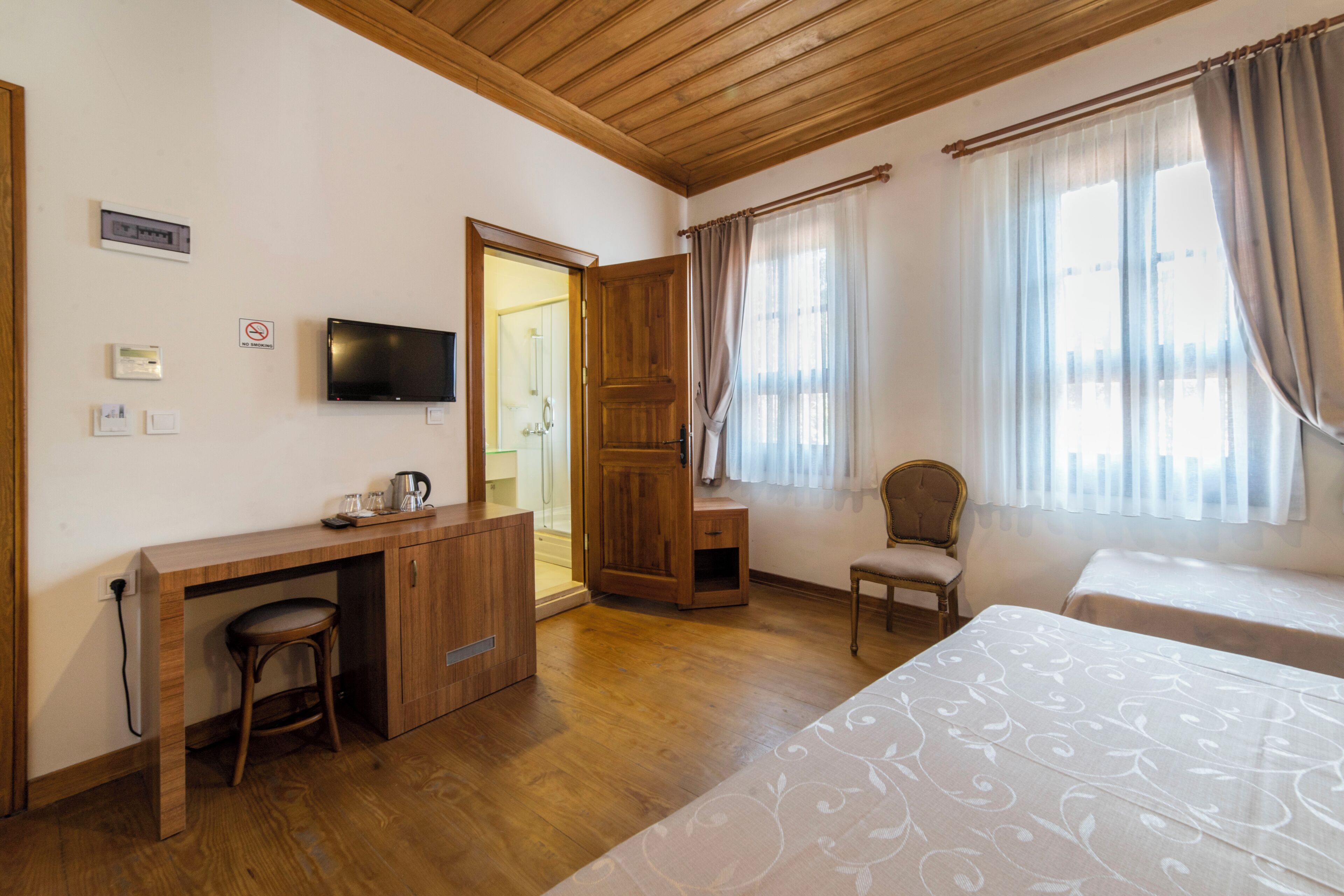 Um quarto com uma mesa de madeira, televisão, cama e uma cadeira.