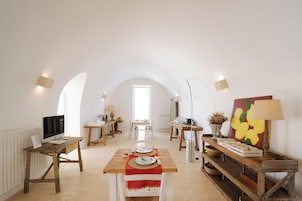 Uma ampla área de refeições com uma mesa de madeira, cadeiras e uma vista através de uma porta em arco.