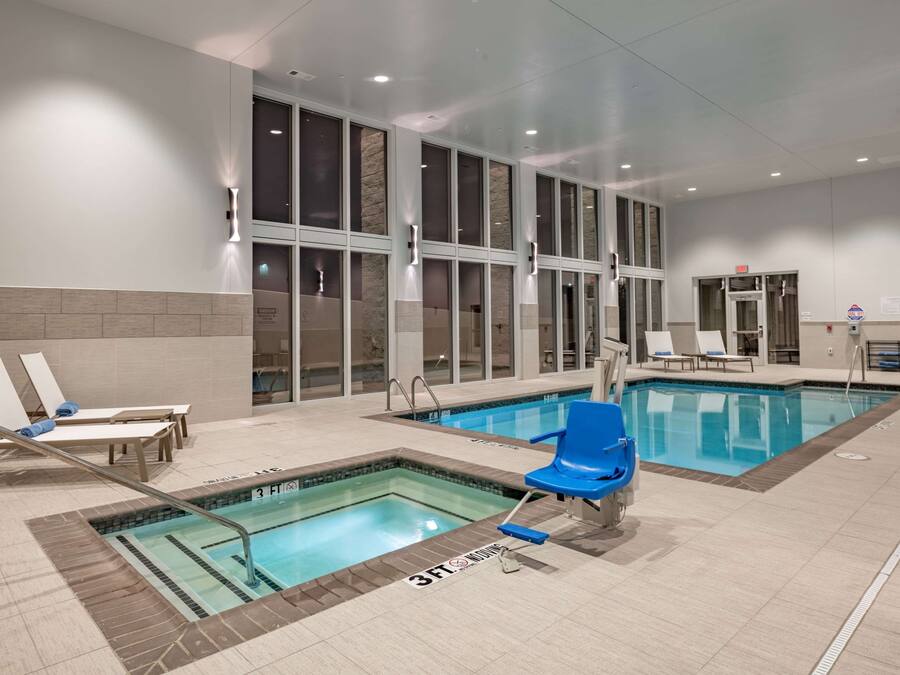 Piscina interna com várias pistas de natação, cadeiras de descanso e um trampolim de 1 metro.