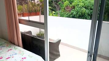 Quarto com cama, janela e vista para um jardim.