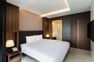 Quarto de hotel moderno com uma cama grande, abajures, telefone e espelho.