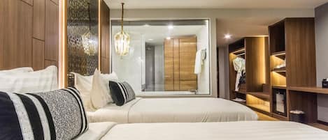 Quarto de hotel moderno com uma cama grande, um closet espaçoso e um banheiro visível através de uma porta de vidro.