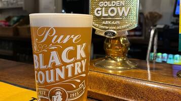Um copo de cerveja com a marcação 'Pure Black Country' e uma torneira identificada como 'Holden's Golden Glow'.