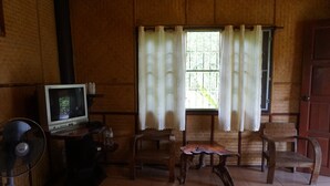 Quarto com televisão, ventoinha e móveis de madeira.
