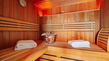 Uma sauna com bancos de madeira, um balde de madeira e um relógio na parede.
