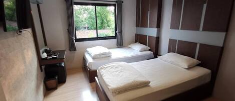 Quarto de hotel com duas camas, televisão de tela plana, aparelho de ar condicionado e janela com cortinas.