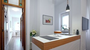 Cozinha moderna com bancada de madeira, pia e tapete preto. Há um quadro na parede e um vaso com planta.