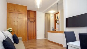 Uma sala de estar moderna com um sofá, uma mesa de jantar, uma televisão e armários de madeira.