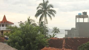 Um edifício à beira-mar com telhado de telhas vermelhas, uma palmeira e um reservatório de água.