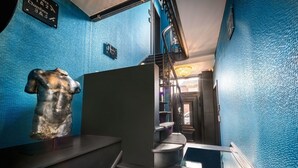 Uma escadaria com uma parede azul texturizada, uma escultura de metal e uma placa com números de quartos.