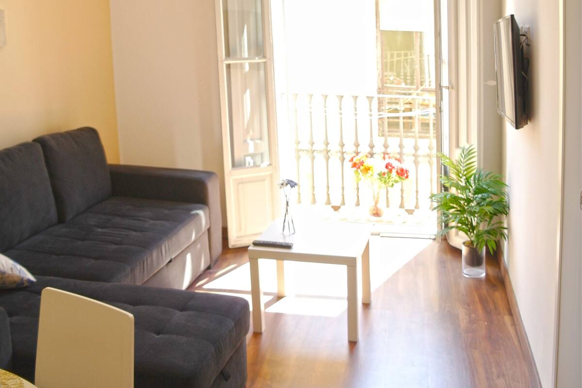 Sala de estar com sofá, uma mesinha e um vaso de planta.