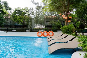 Piscina com cadeiras de descanso e boias laranja.